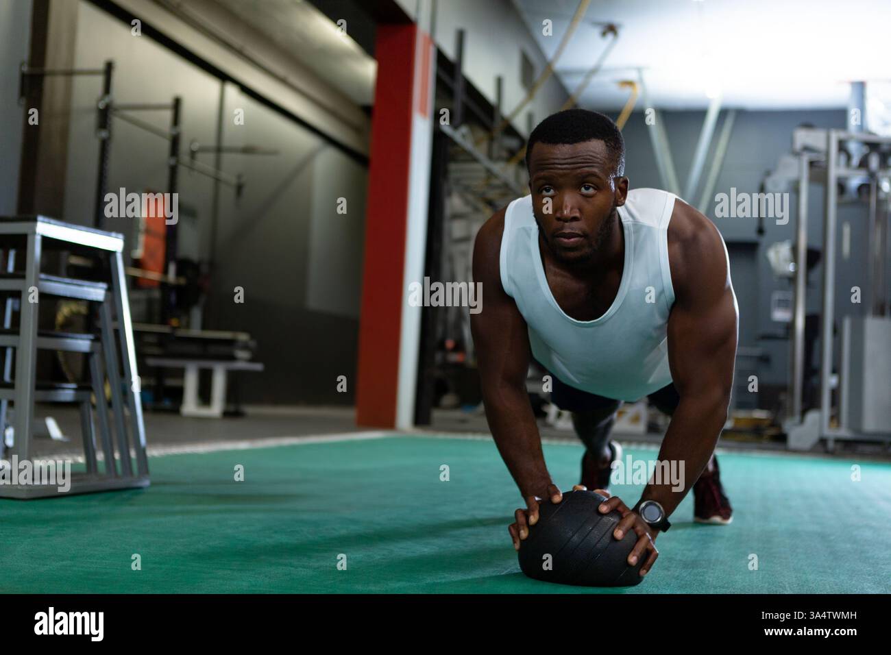 Athletic man doing plank exercise with medicine ball in modern gym ...