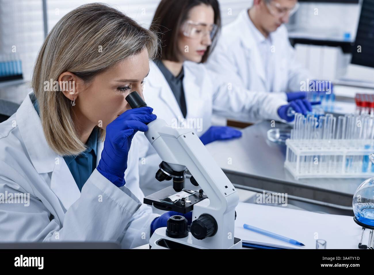 Scientist working with microscope at table in laboratory Stock Photo ...