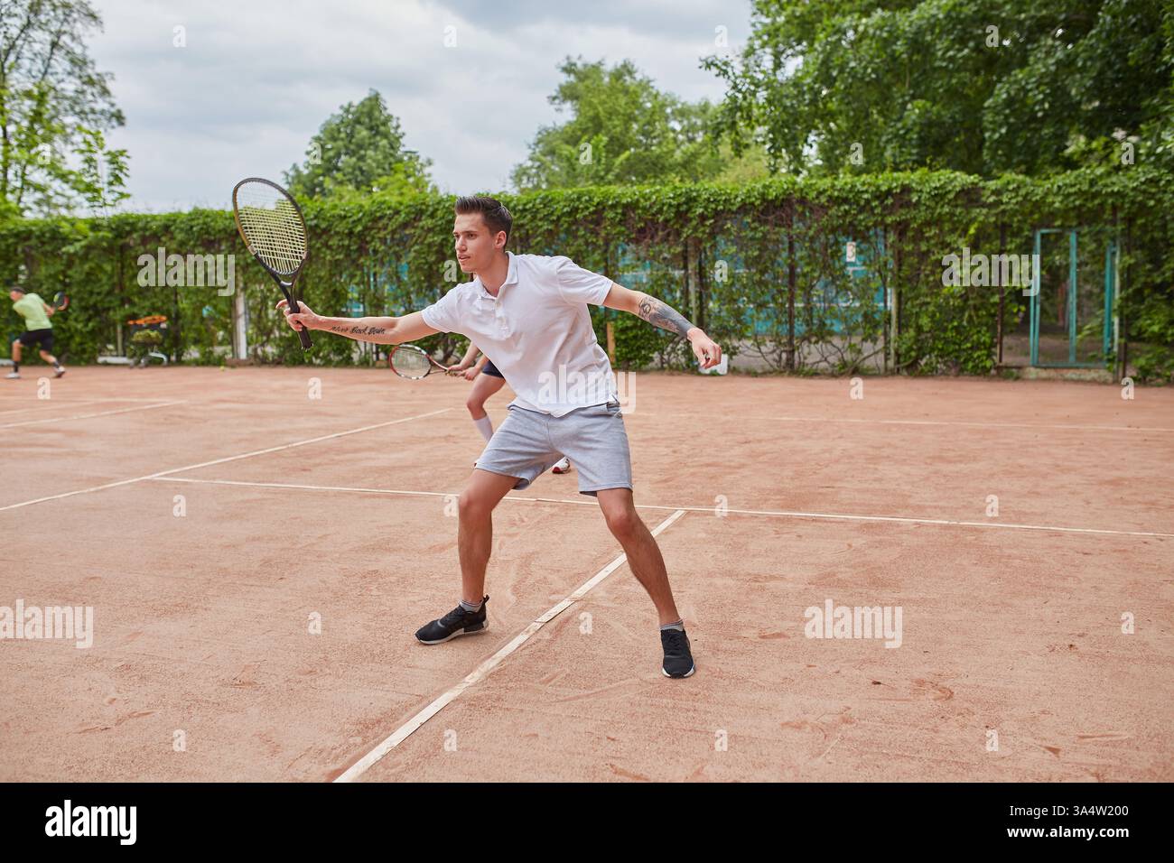 A young man in a ready position holding a tennis racket, preparing for ...