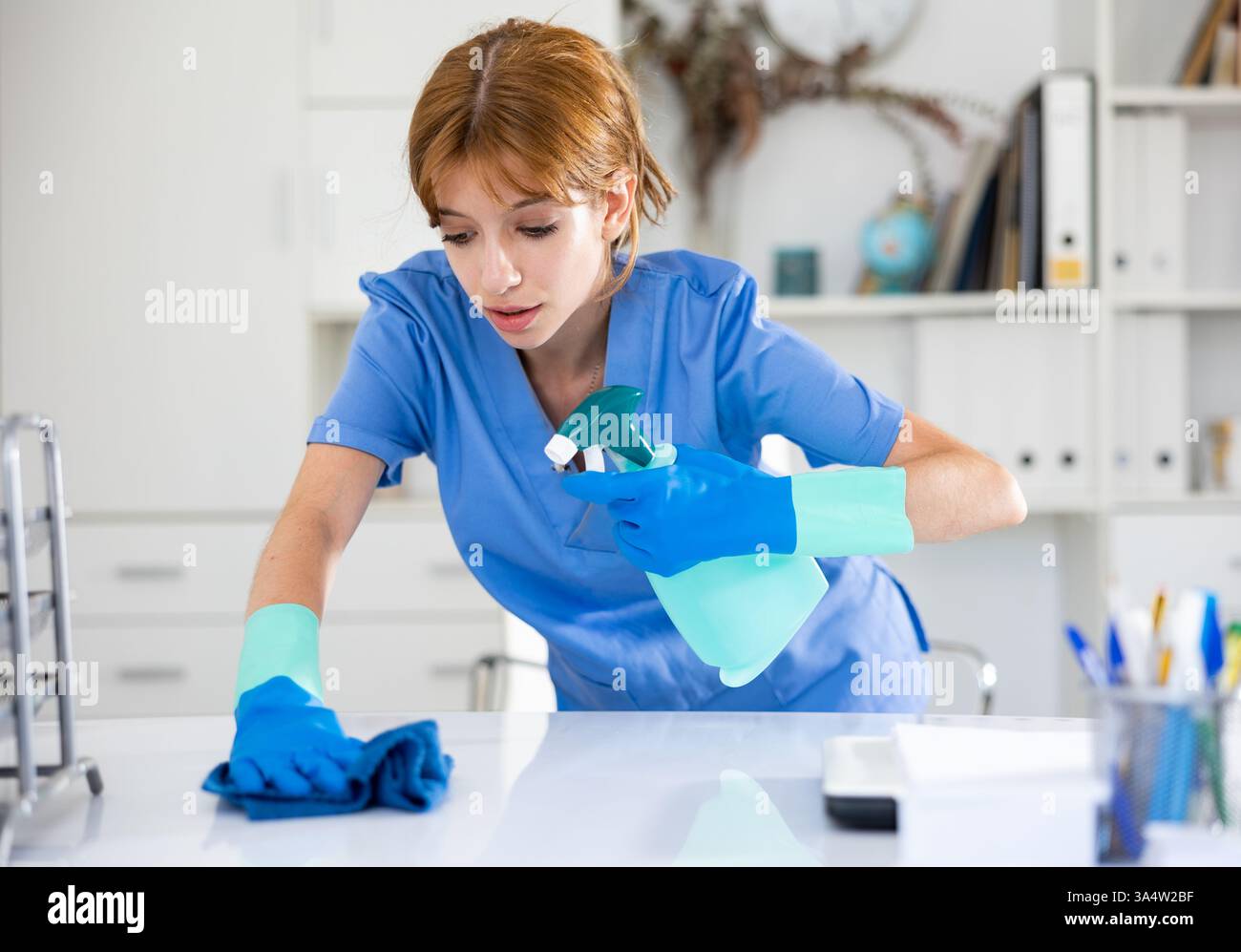 Cleaning lady of cleaning company wipes dust from table in office Stock ...