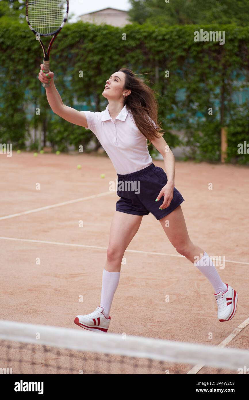 A female tennis player performing a forehand swing on a clay court ...