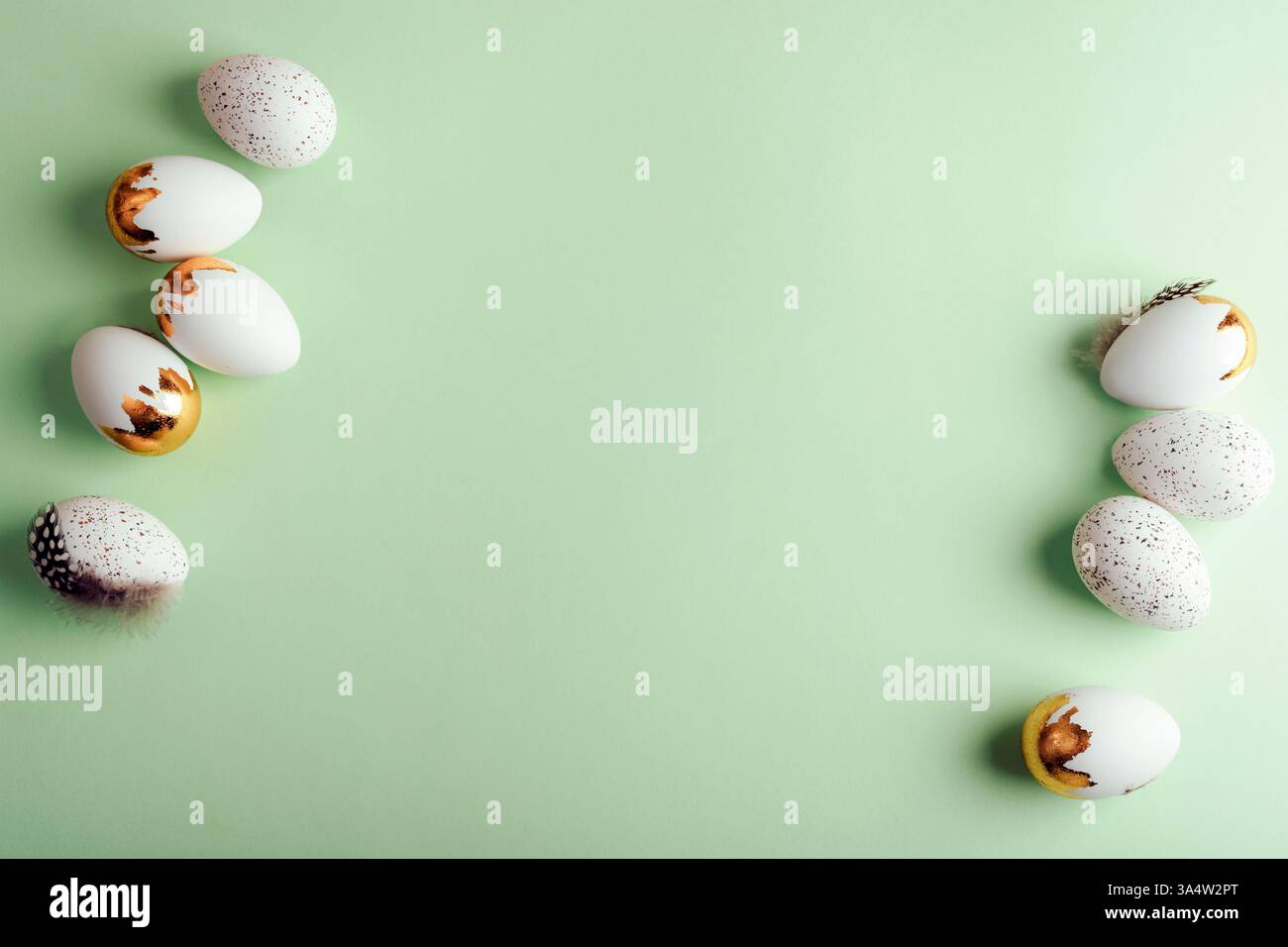 White and gold Easter eggs with speckled patterns and feathers arranged ...