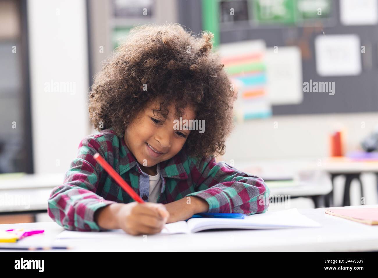 In school, happy child writing in notebook, enjoying classroom ...