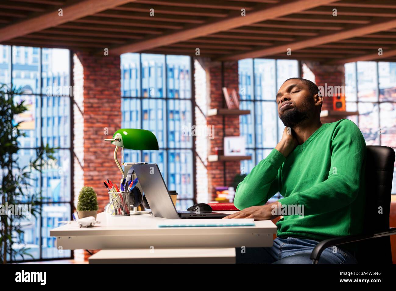 Tired man with eyes closed at desk in apartment feeling exhausted after ...