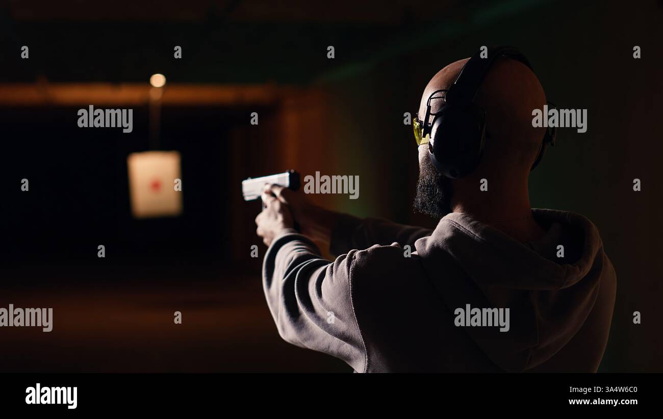 Shooting gallery customer using pistol to hit targets, wearing ...