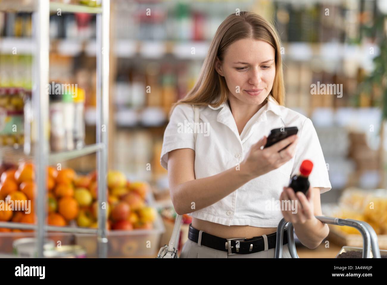 Female shopper scanning QR code on bottle soy sauce label in grocery ...