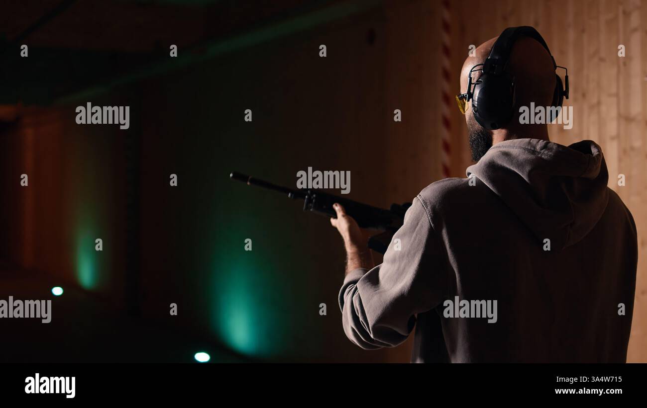 Man in firing range doing shooting activity with rifle, wearing ...