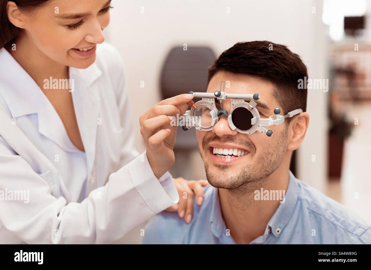 Optometrist conducting eye exam with patient wearing trial frame ...