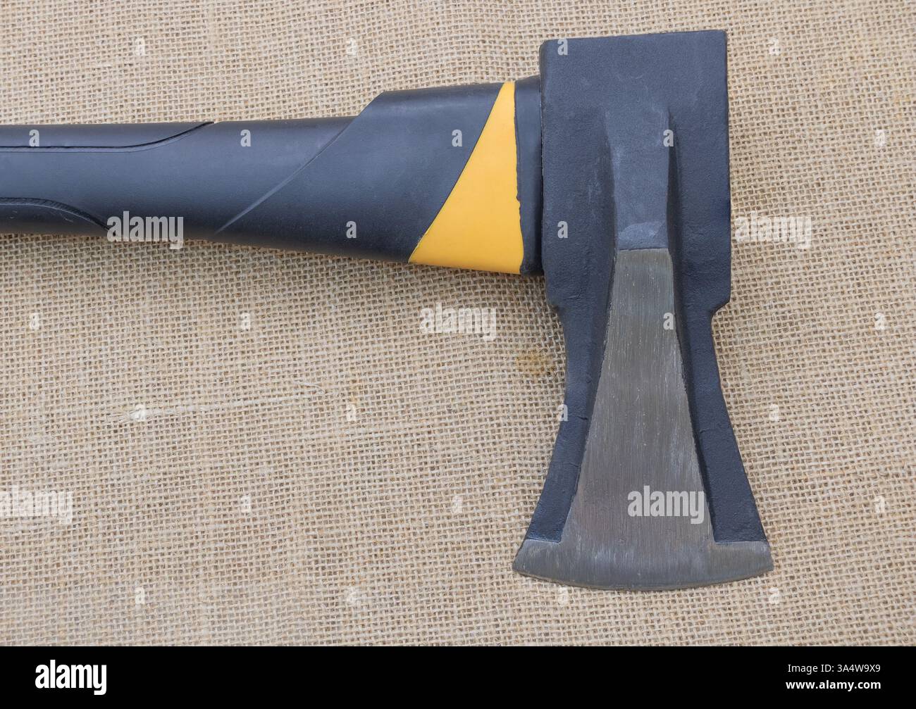 A straight black and yellow ax with an oversized head, resting on ...