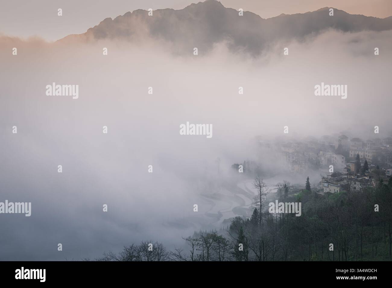 Orange sunrise sky at the rice terraces, dense fog and Duoyishu village ...