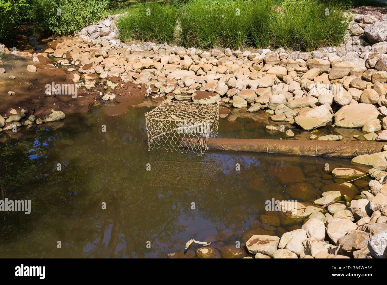 Pond under construction with water intake pipe protected with a wire ...