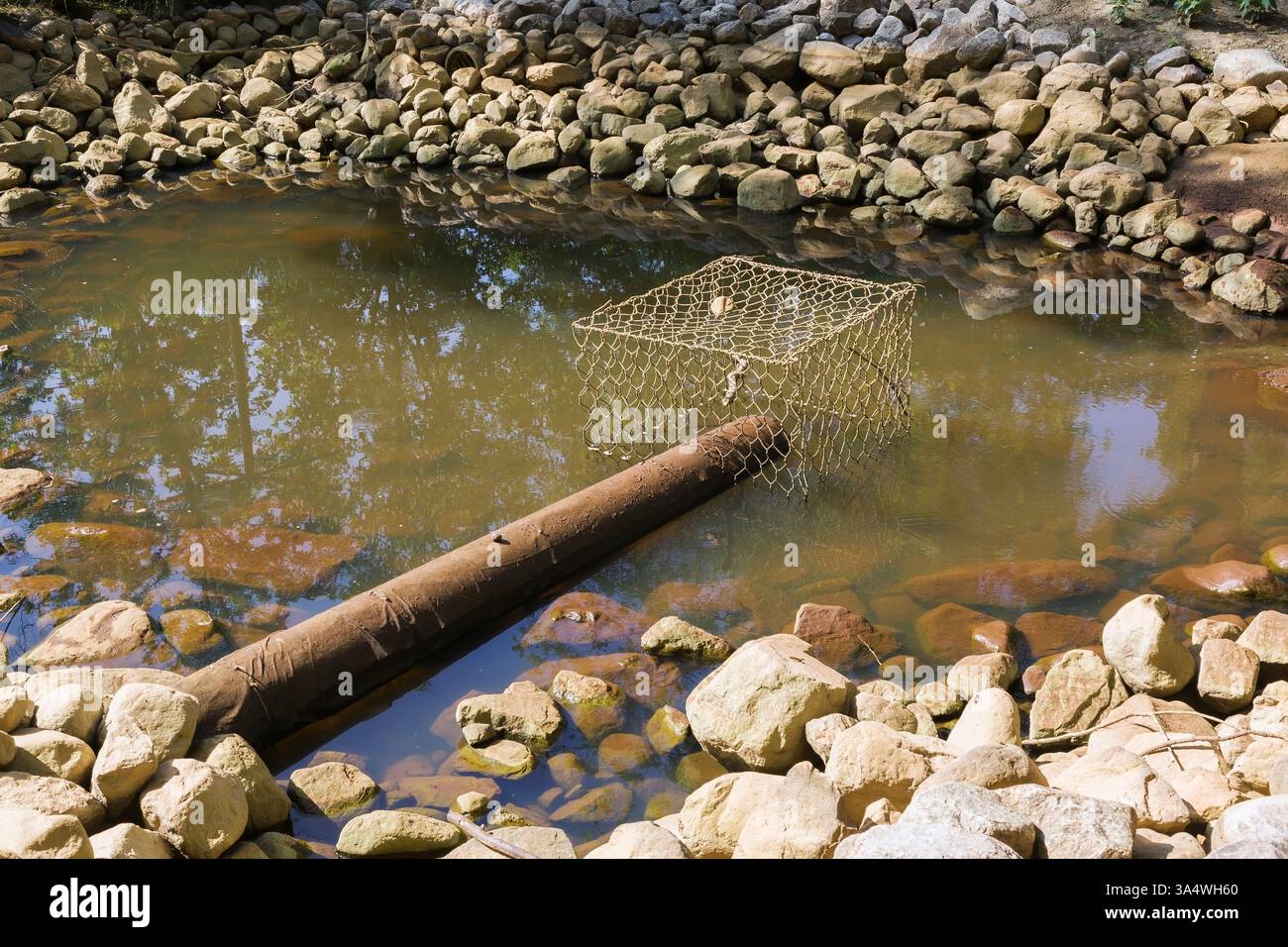 Pond under construction with water intake pipe protected with a wire ...