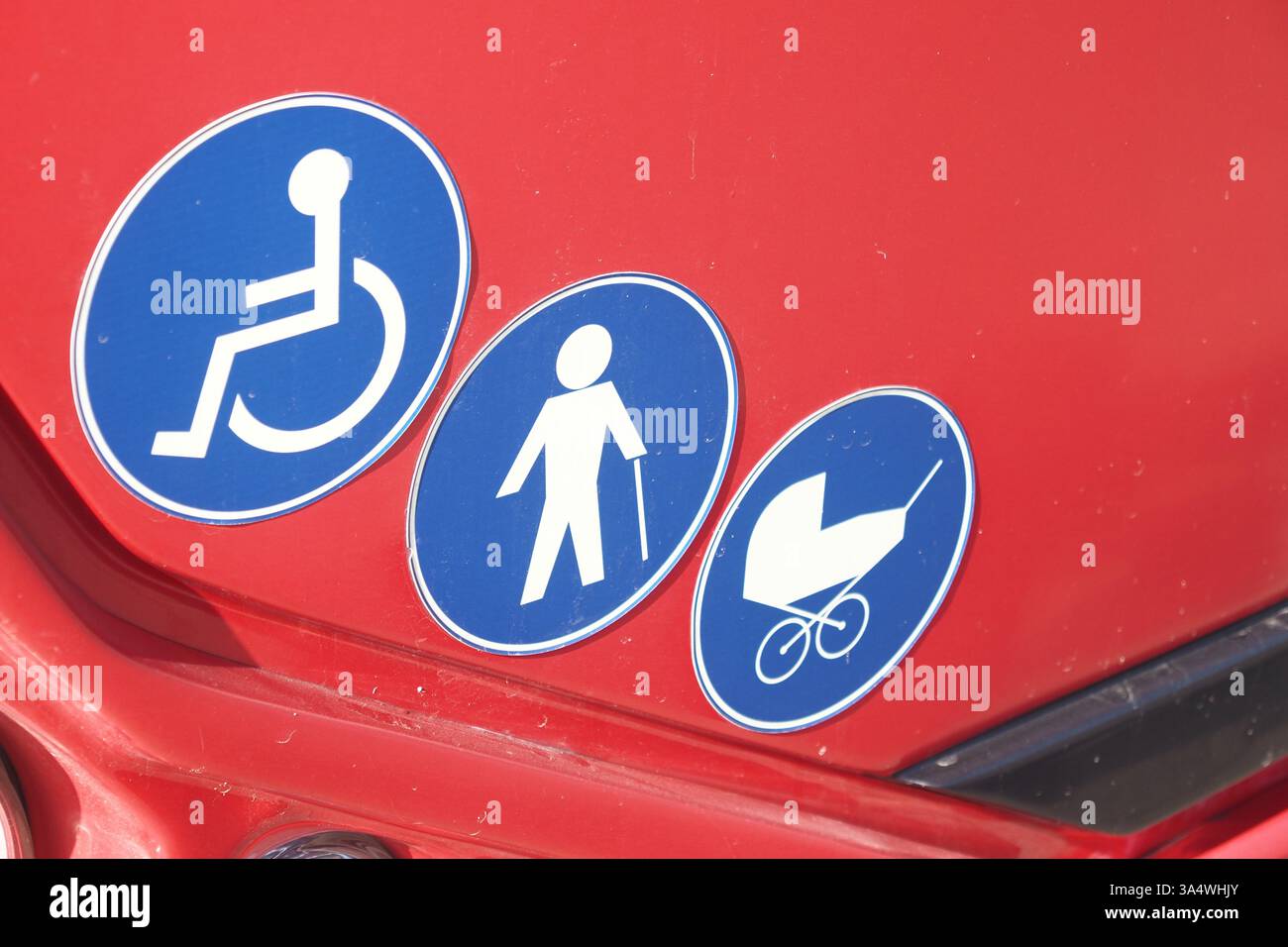 Various accessibility symbols displayed on a red vehicle's surface ...