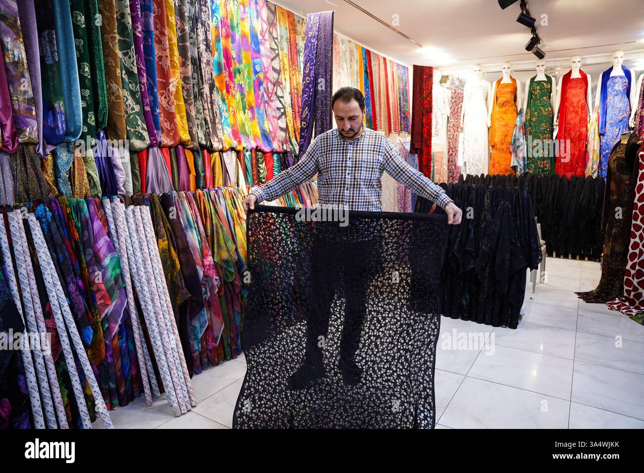 An Iraqi Kurdish man displays traditional Kurdish clothing fabrics in ...