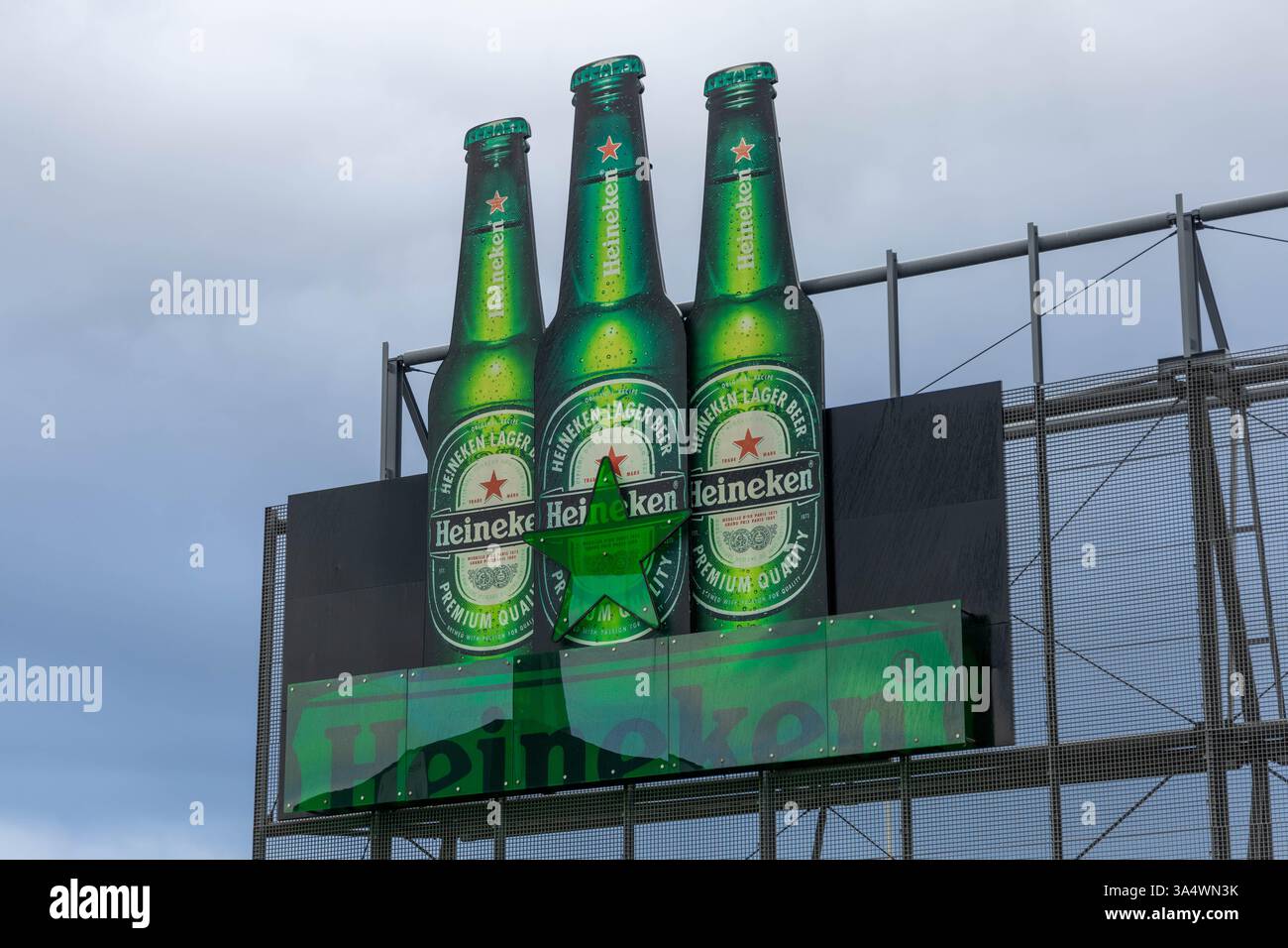 . Heineken bottle sign and logo against a cloudy sky. Heineken is a ...