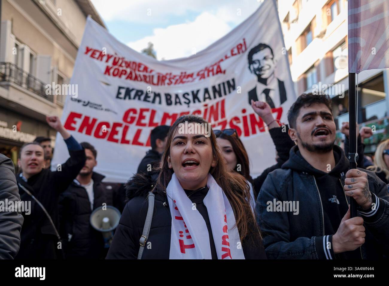 Izmir, Turkey. 19th Mar, 2025. People chant slogans and hold banners ...