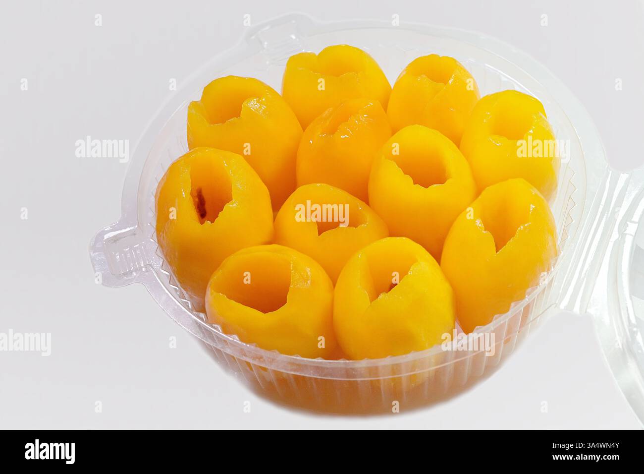 A plastic punnet container with skinned and deseeded ripe yellow marian ...