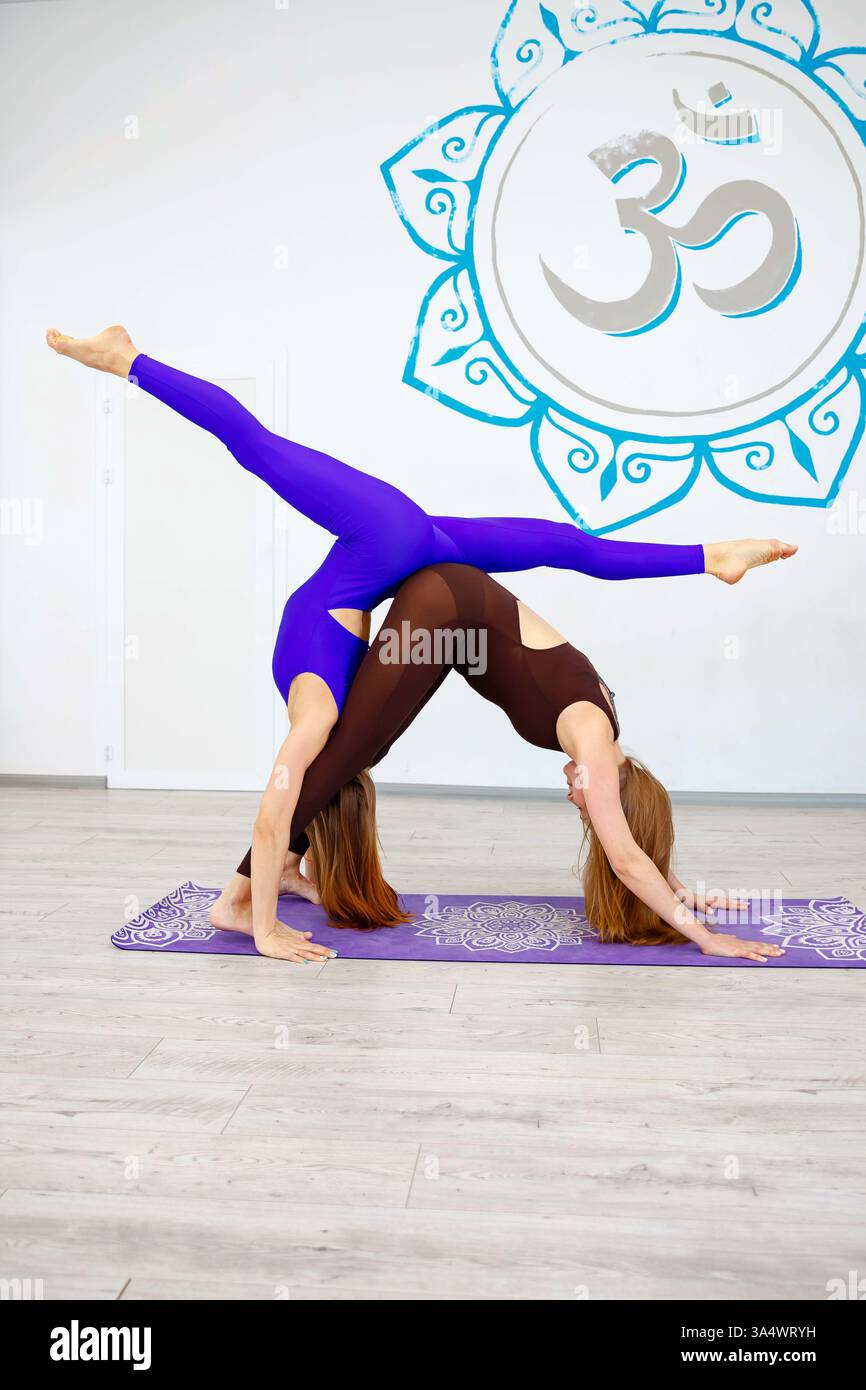 Two women performing an advanced acro yoga pose Stock Photo - Alamy
