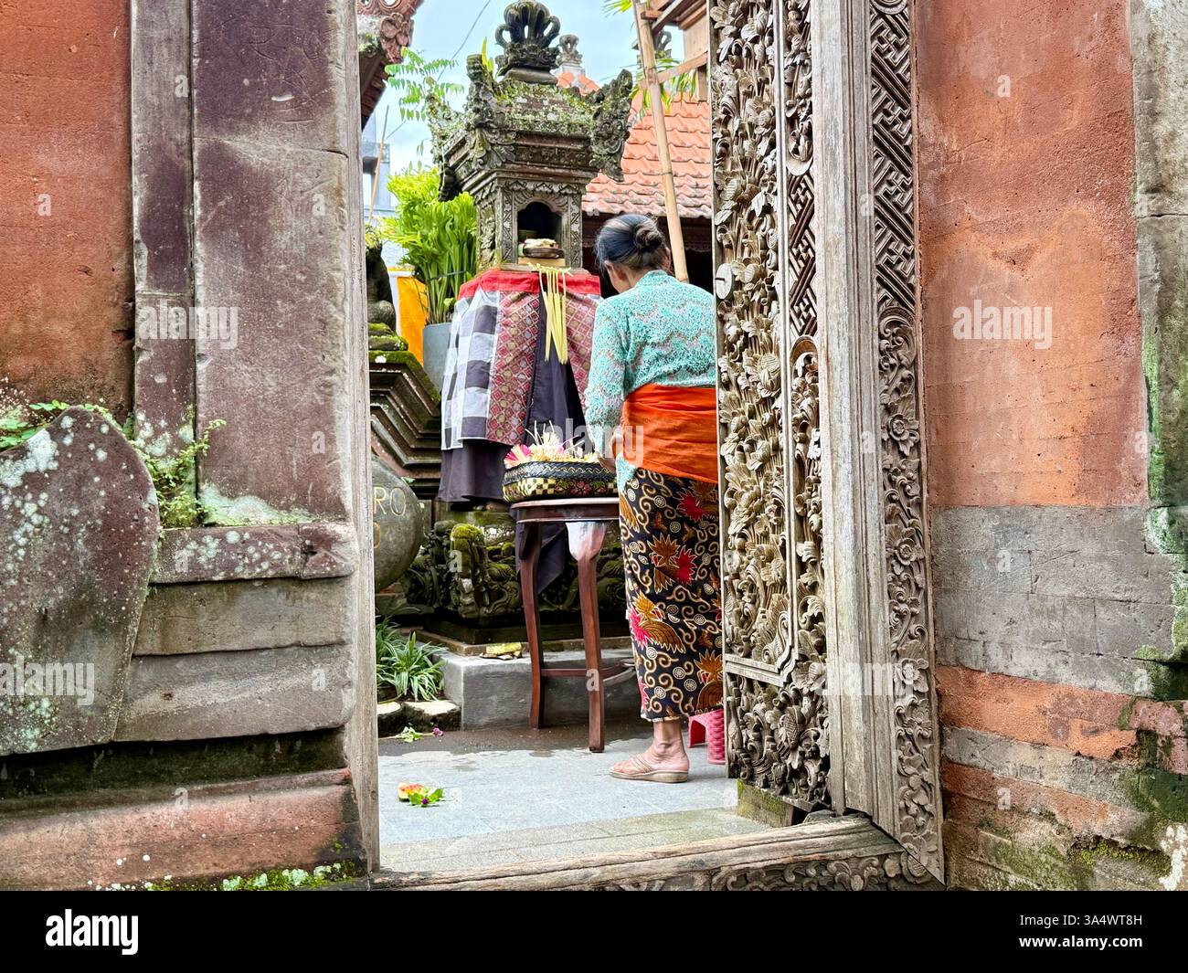 Ubud, Indonesia. 19th Mar, 2025. A Balinese woman in traditional dress prepares for a ceremony ...