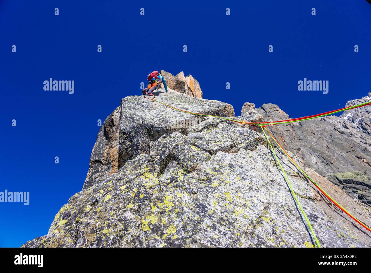 Alpinists climbing granite mountain walls in the Alps. Difficult alpine ...