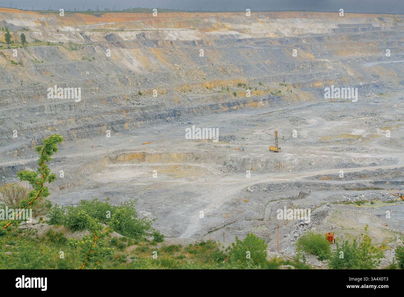A vast open-pit mine with visible excavation sites, dirt roads, and ...