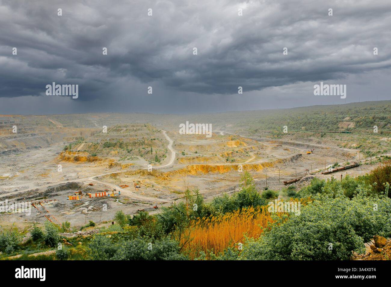 Open pit mining under a stormy sky with excavations, heavy equipment ...