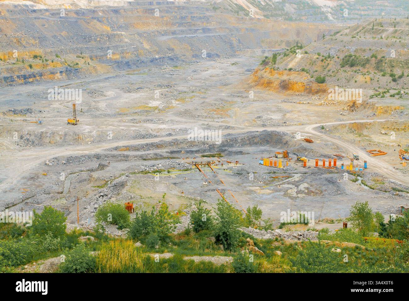 A vast open-pit mine with visible excavation sites, dirt roads, and ...