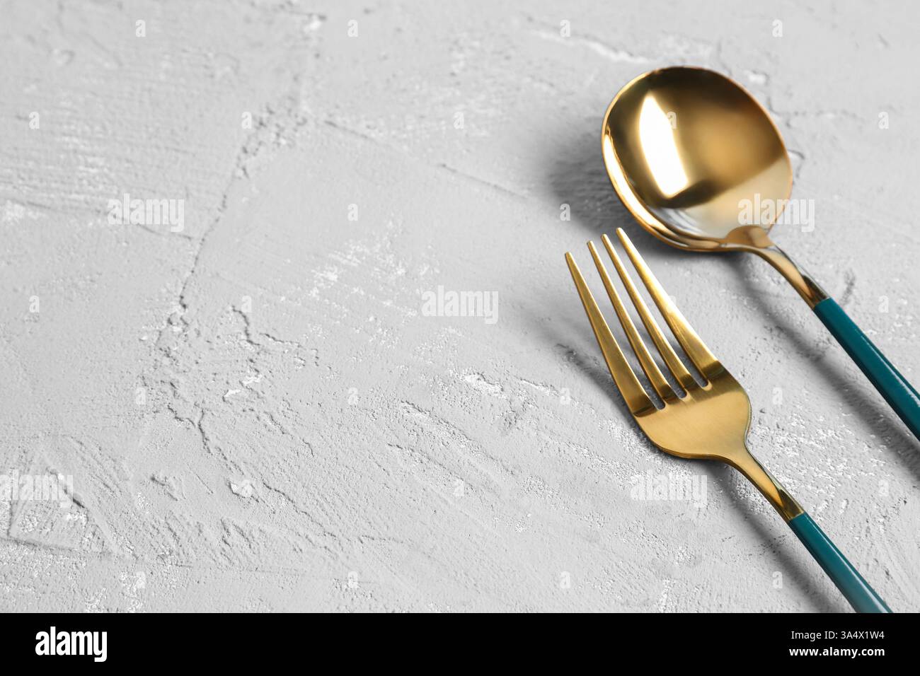 Golden spoon and fork with blue handles on grey background Stock Photo ...