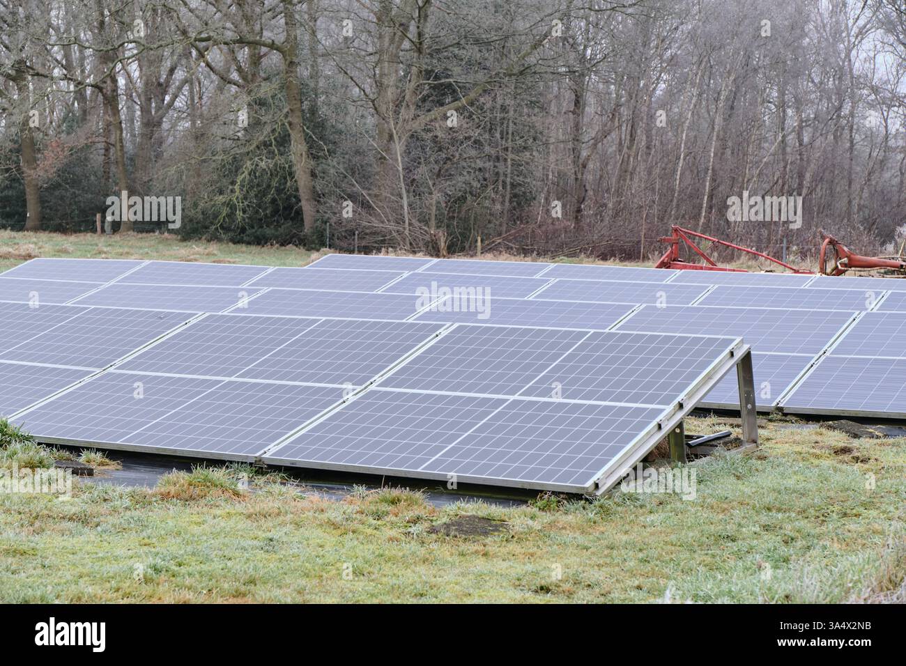 A small solar farm with photovoltaic panels on frosty grass near a ...