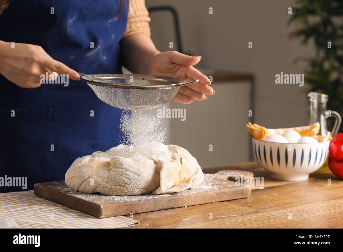 Woman with sieve sprinkling flour on fresh dough in kitchen Stock Photo ...