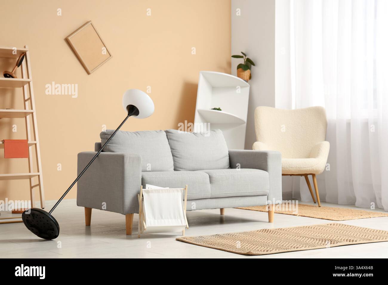 Interior of messy living room with grey sofa, overturned standard lamp ...