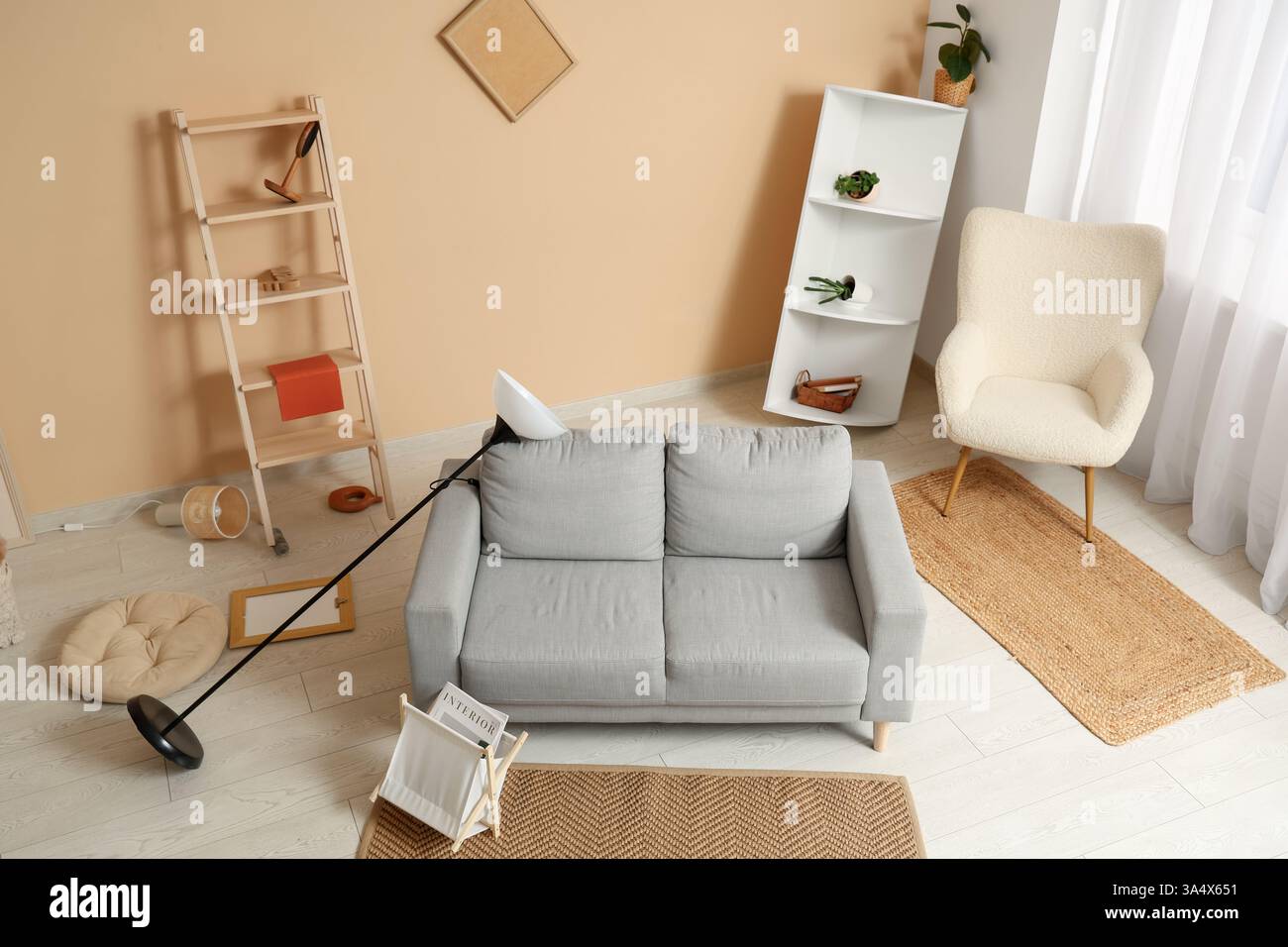 Interior of messy living room with grey sofa, overturned standard lamp ...