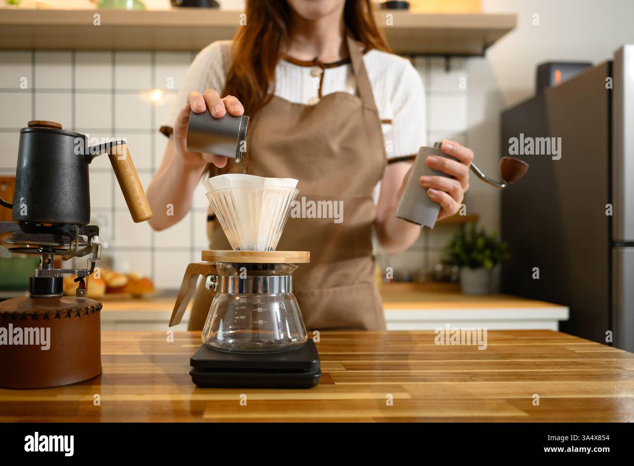 Close up of hand pouring ground coffee into a paper filter in a glass ...
