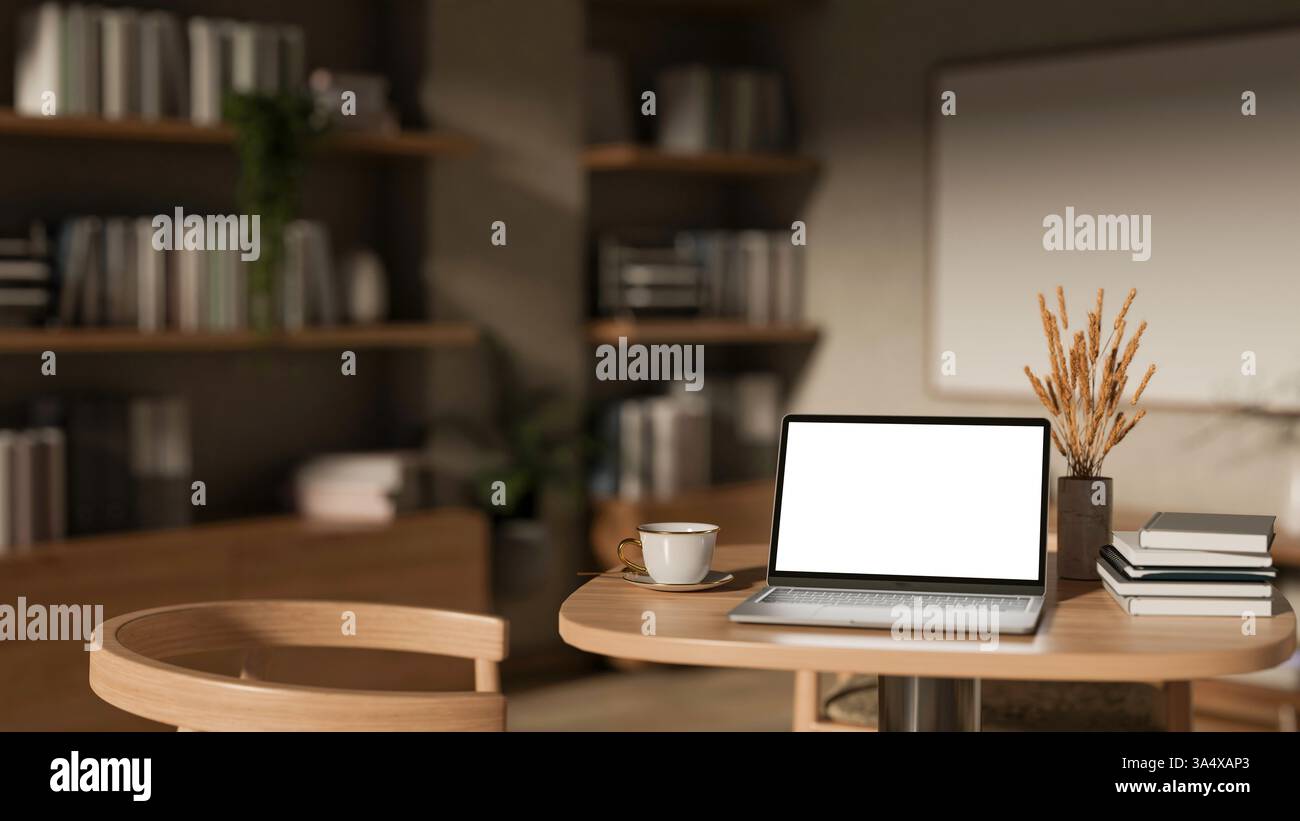 The white screen laptop place between a cup and books on a round wooden ...