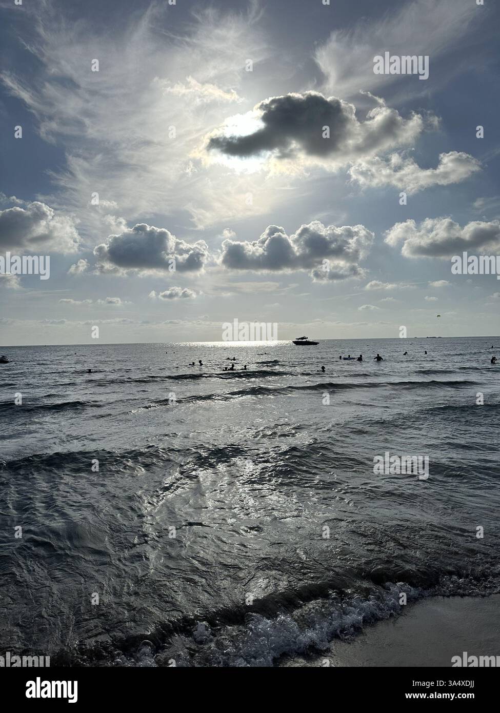 A peaceful beach scene with soft waves and a sky full of clouds. The ...