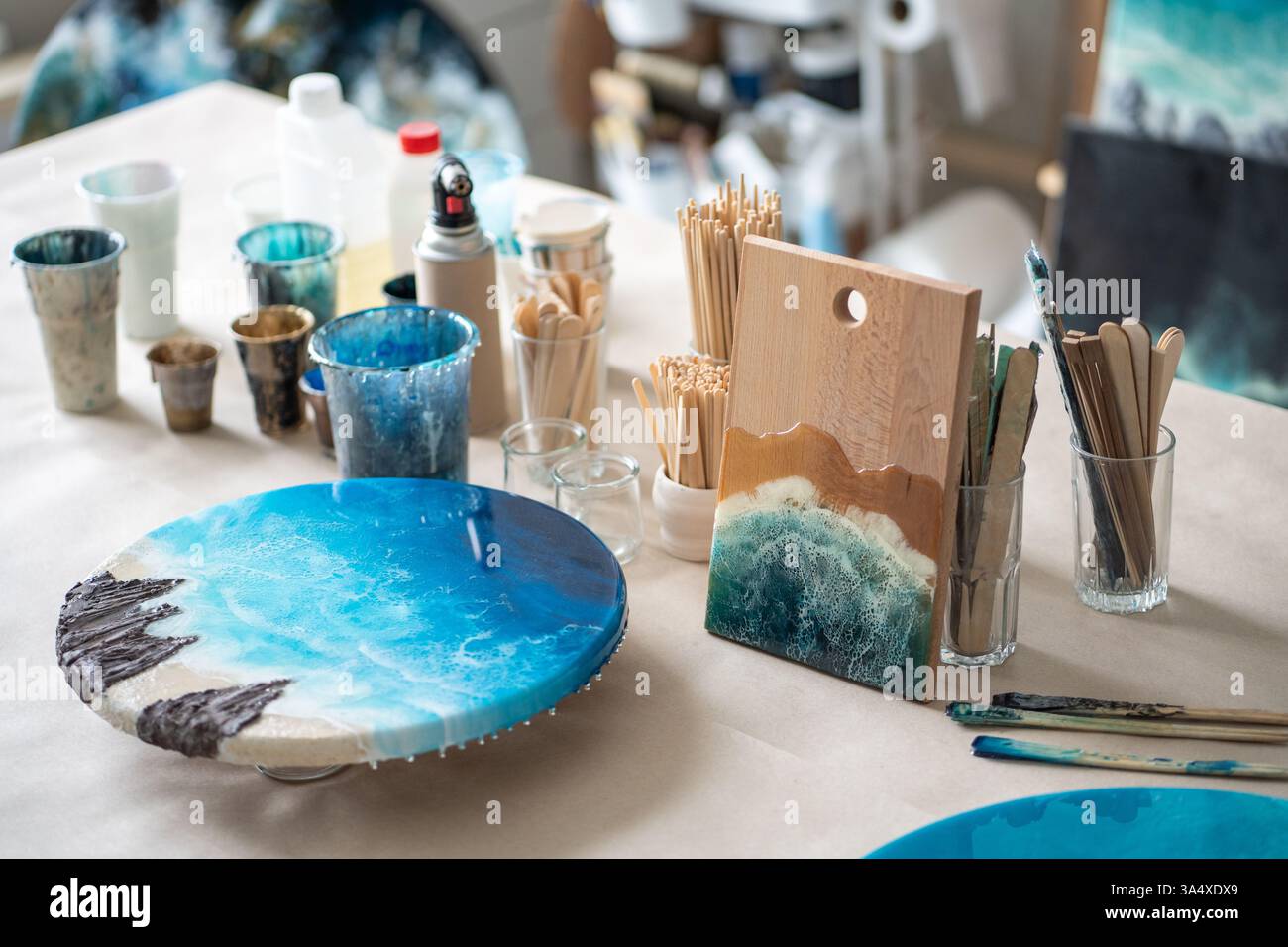 Resin epoxy artworks on craft table with paintbrushes, mixing cups ...