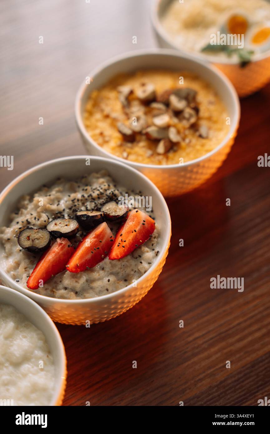 4 types of porridge in white bowls on a wooden background, oatmeal, corn, millet and rice Stock ...