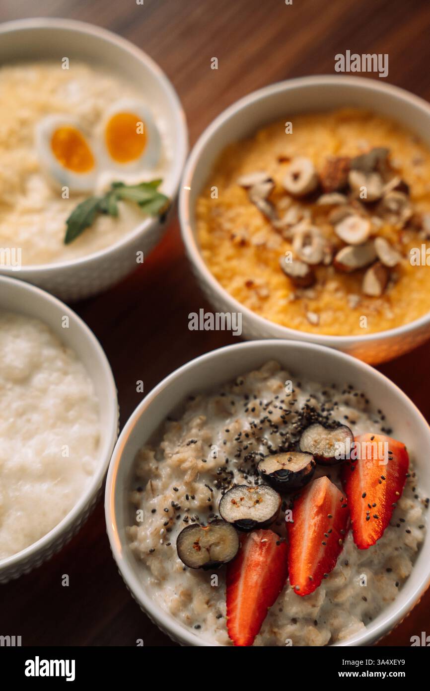 4 types of porridge in white bowls on a wooden background, oatmeal, corn, millet and rice Stock ...