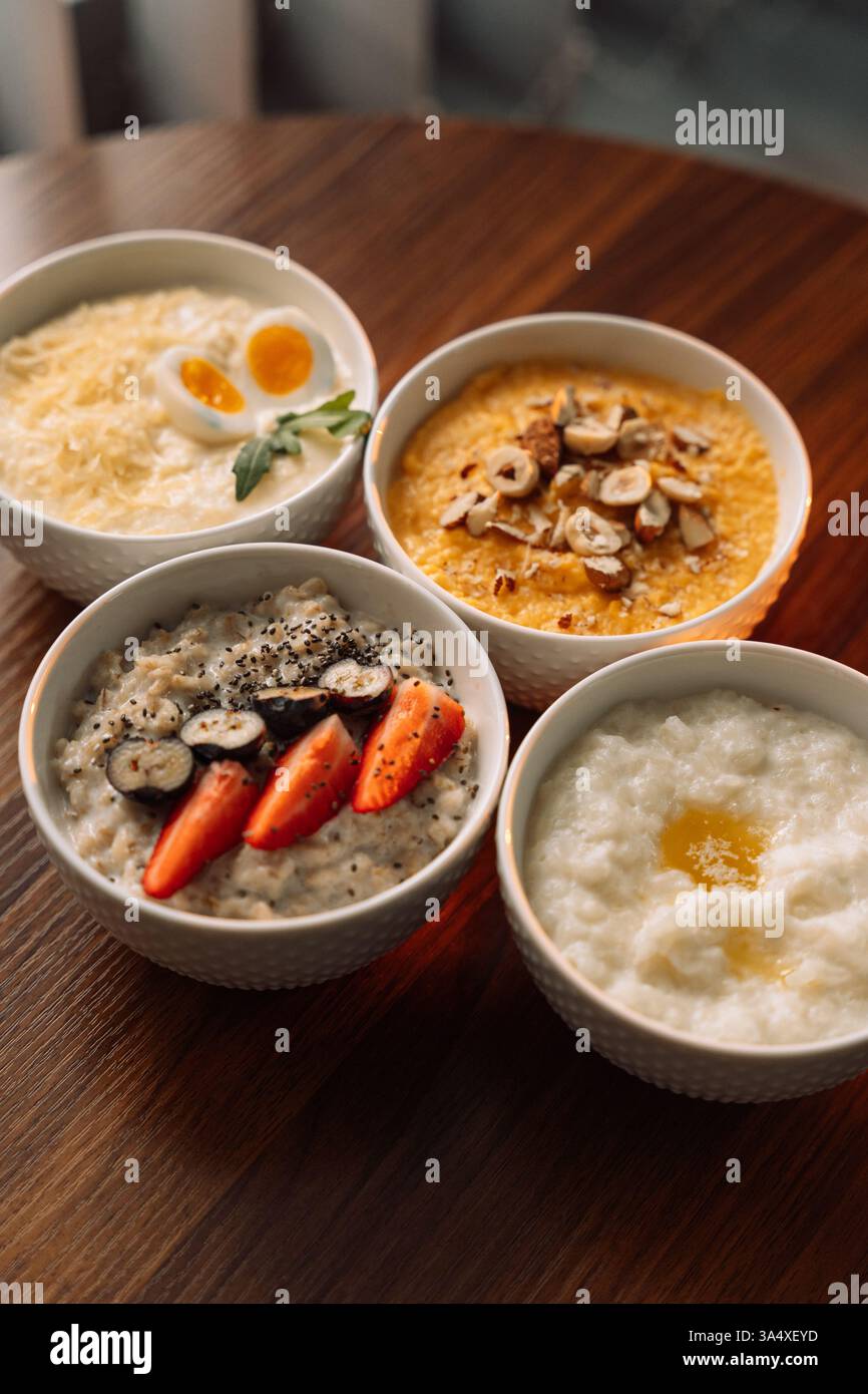 4 types of porridge in white bowls on a wooden background, oatmeal, corn, millet and rice Stock ...
