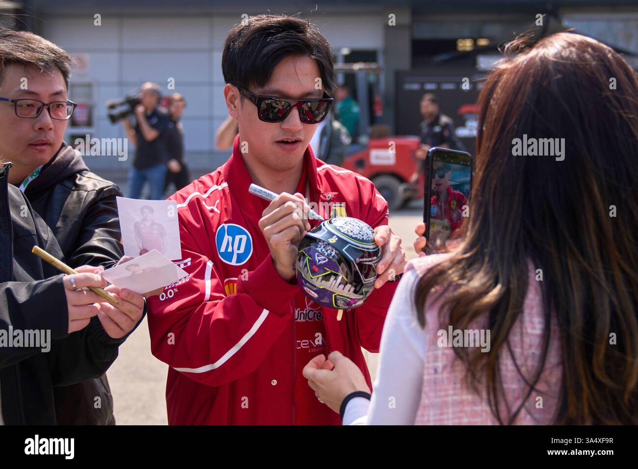 Ferrari reserve driver Zhou Guanyu of China signs his autograph for ...