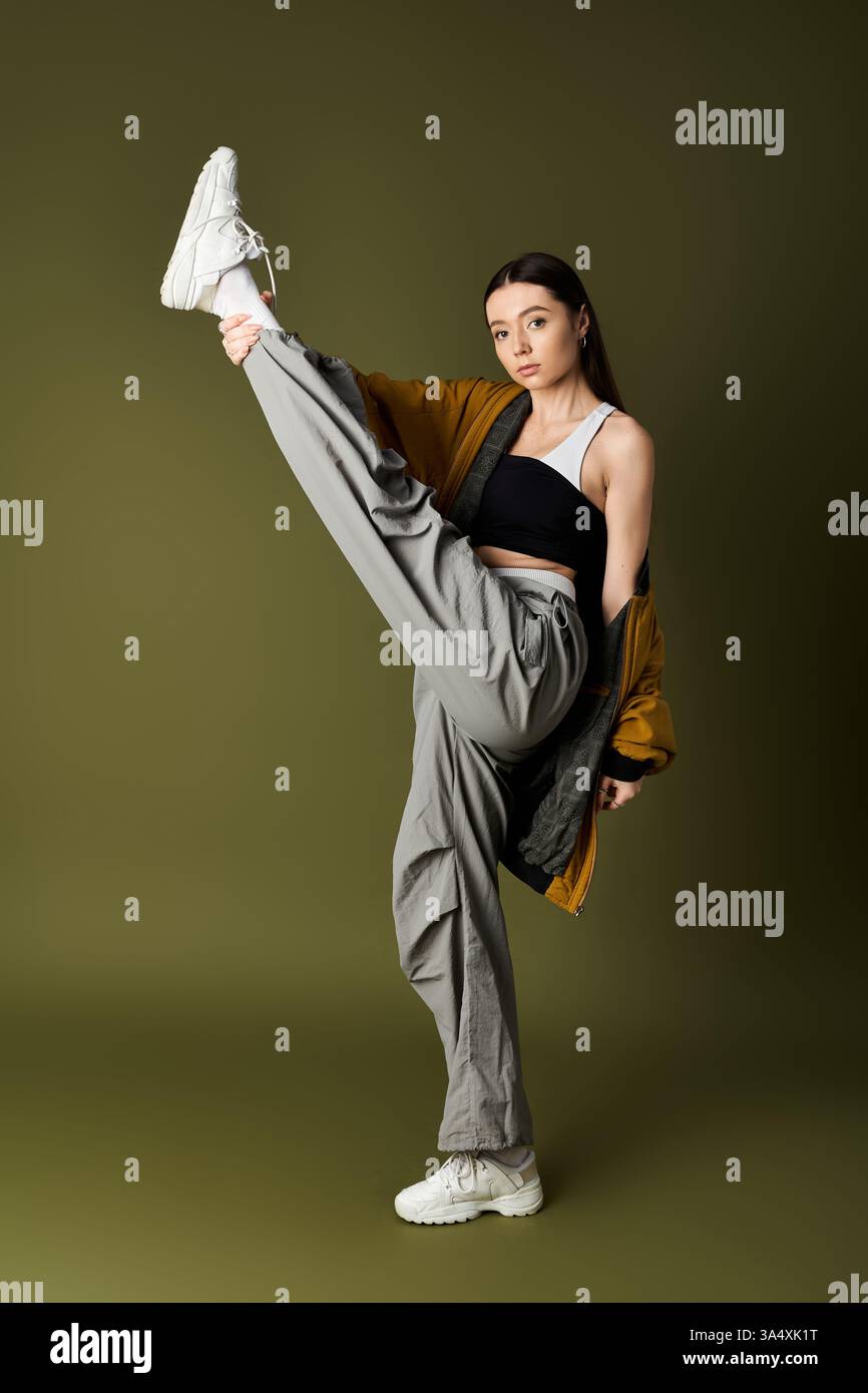A young woman in trendy attire poses confidently in a studio ...