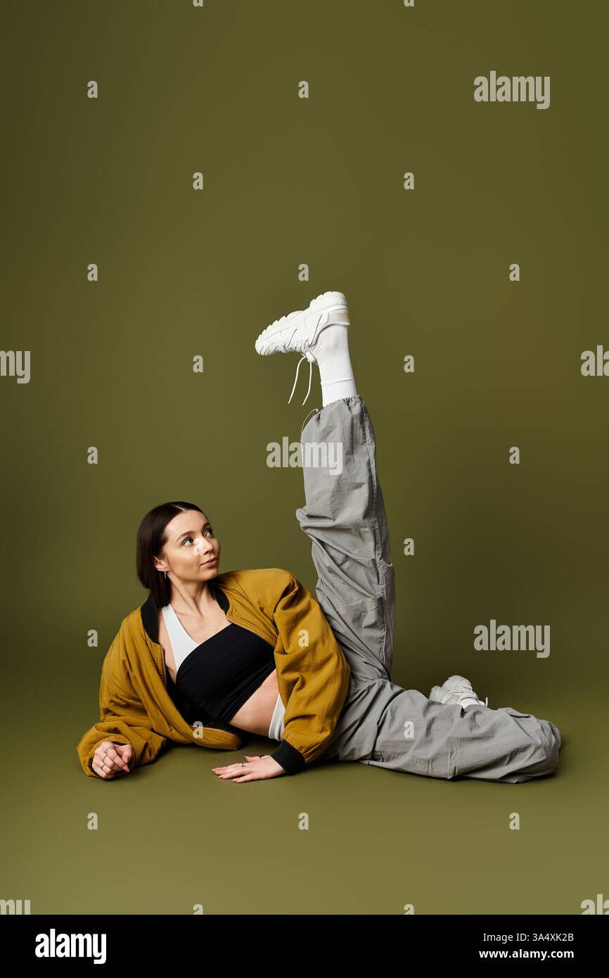 Young woman in stylish attire strikes a unique pose against a green ...