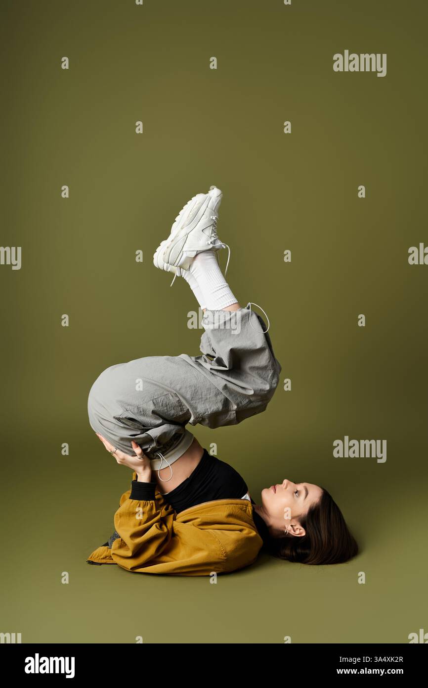 Trendy woman in chic attire performs a playful pose on the floor ...