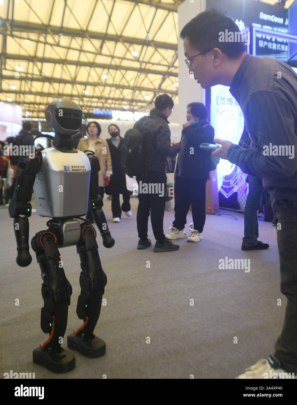 Shanghai, China. 20th Mar, 2025. Spectators look at a humanoid robot at ...