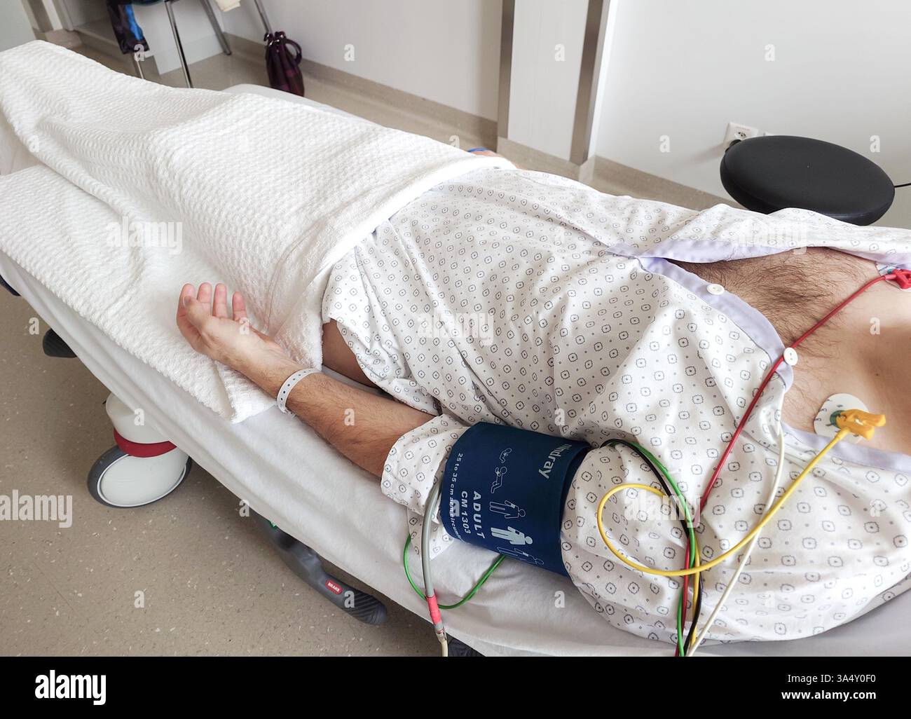 ECG or EKG or electrocardiogram electrodes and a blood pressure monitor connected to a Caucasian ...