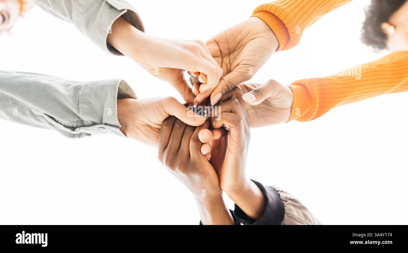 Three young people joining hands, symbolizing teamwork, collaboration, and unity in achieving ...