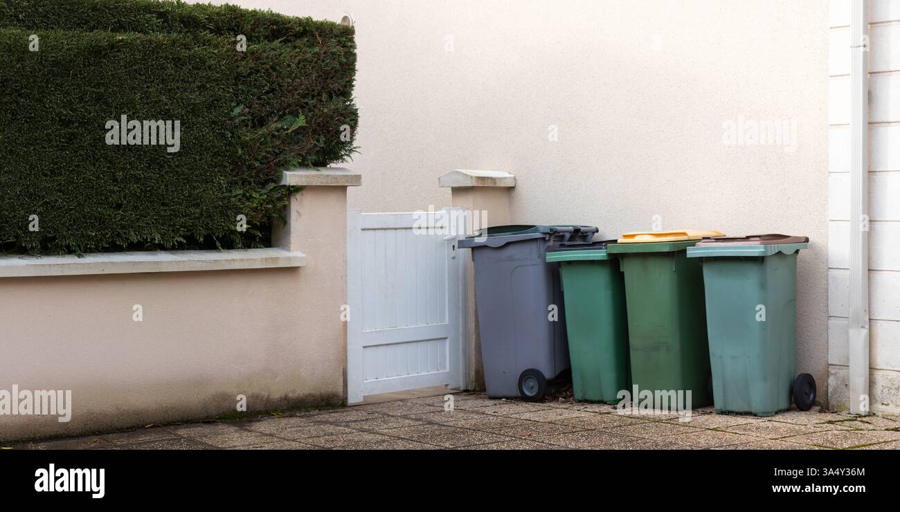 Different colored waste bins are neatly arranged along the side of a ...