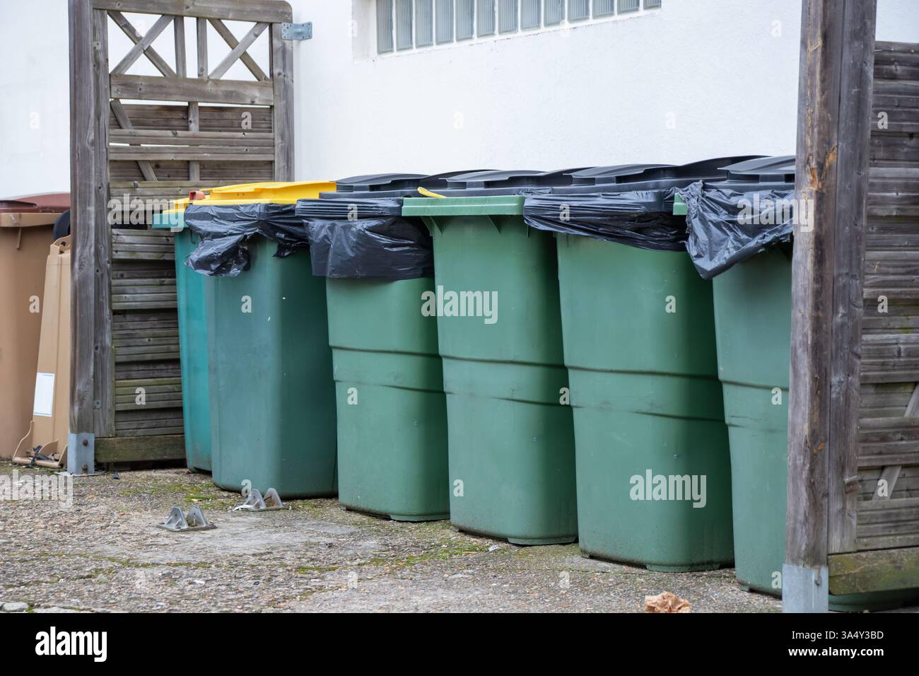 Different colored waste bins are neatly arranged along the side of a ...