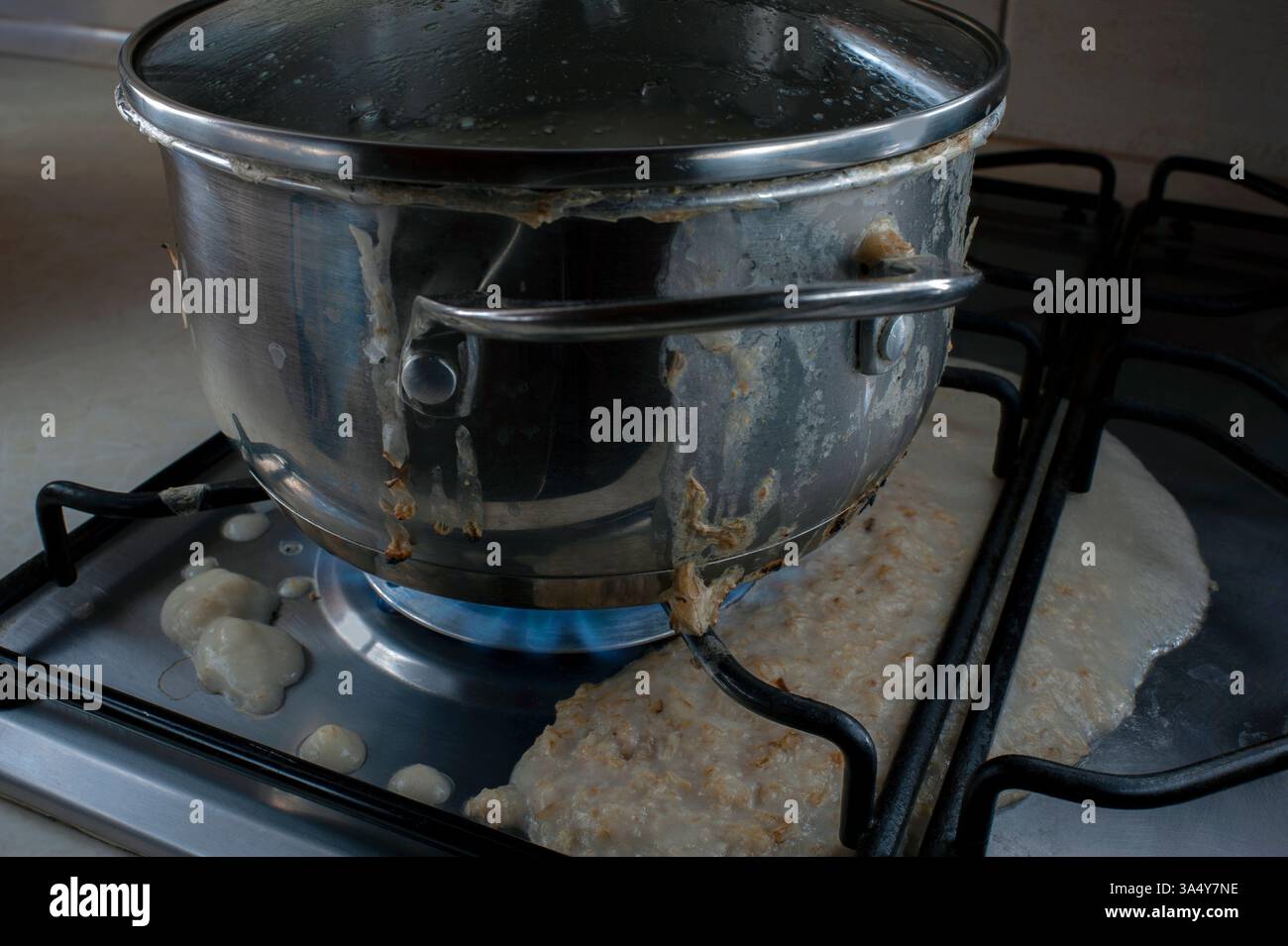 Oatmeal spilled from under the lid of the pot onto the gas stove while ...