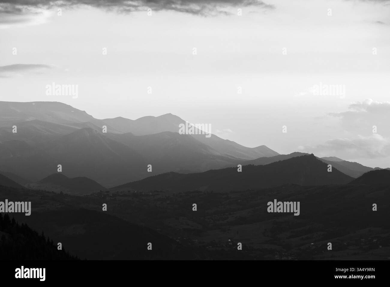 Hazy mountain range with partly cloudy sky. Black and white landscape ...